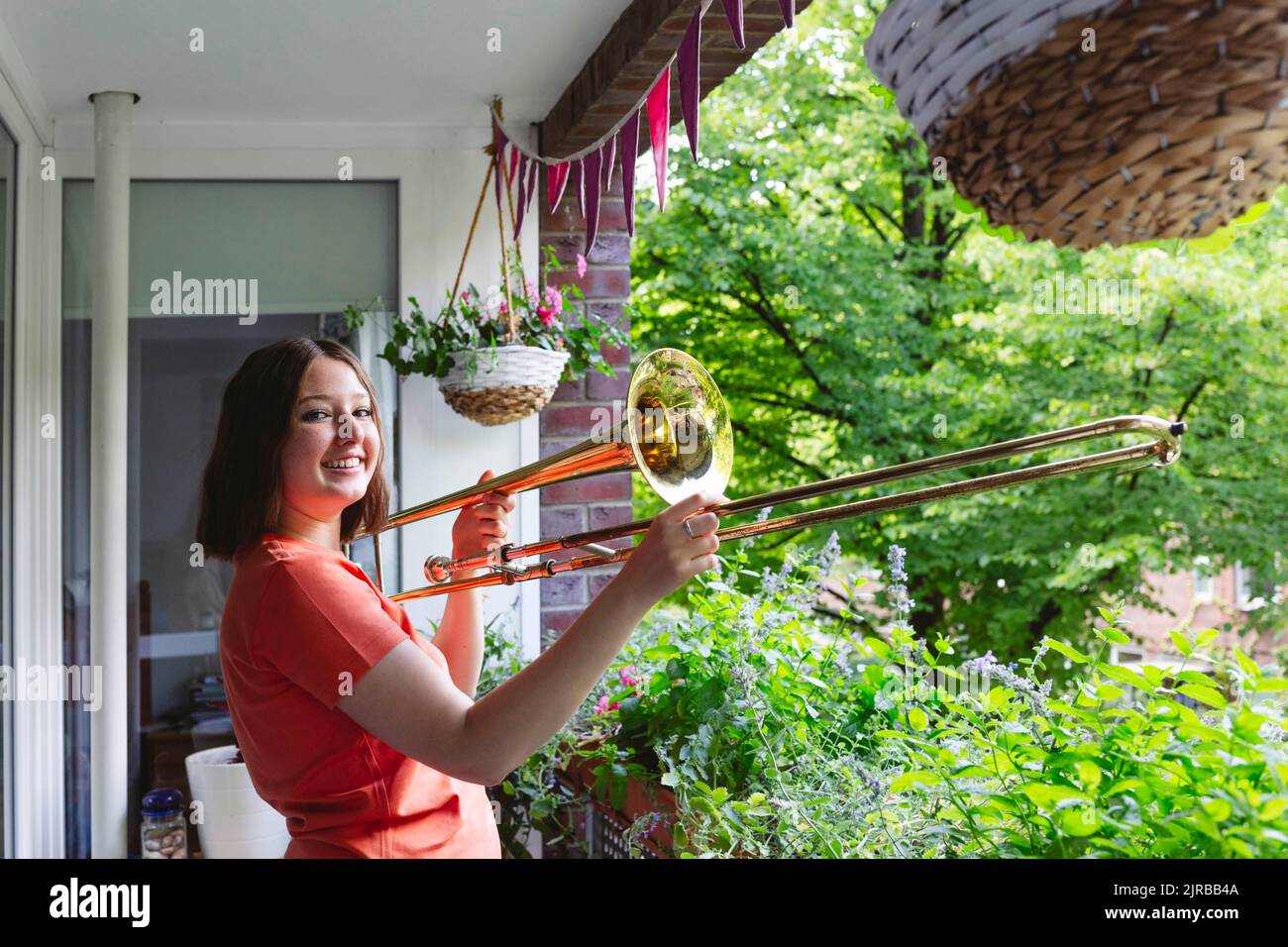 Smiling girl with trombone standing on balcony Stock Photo - Alamy