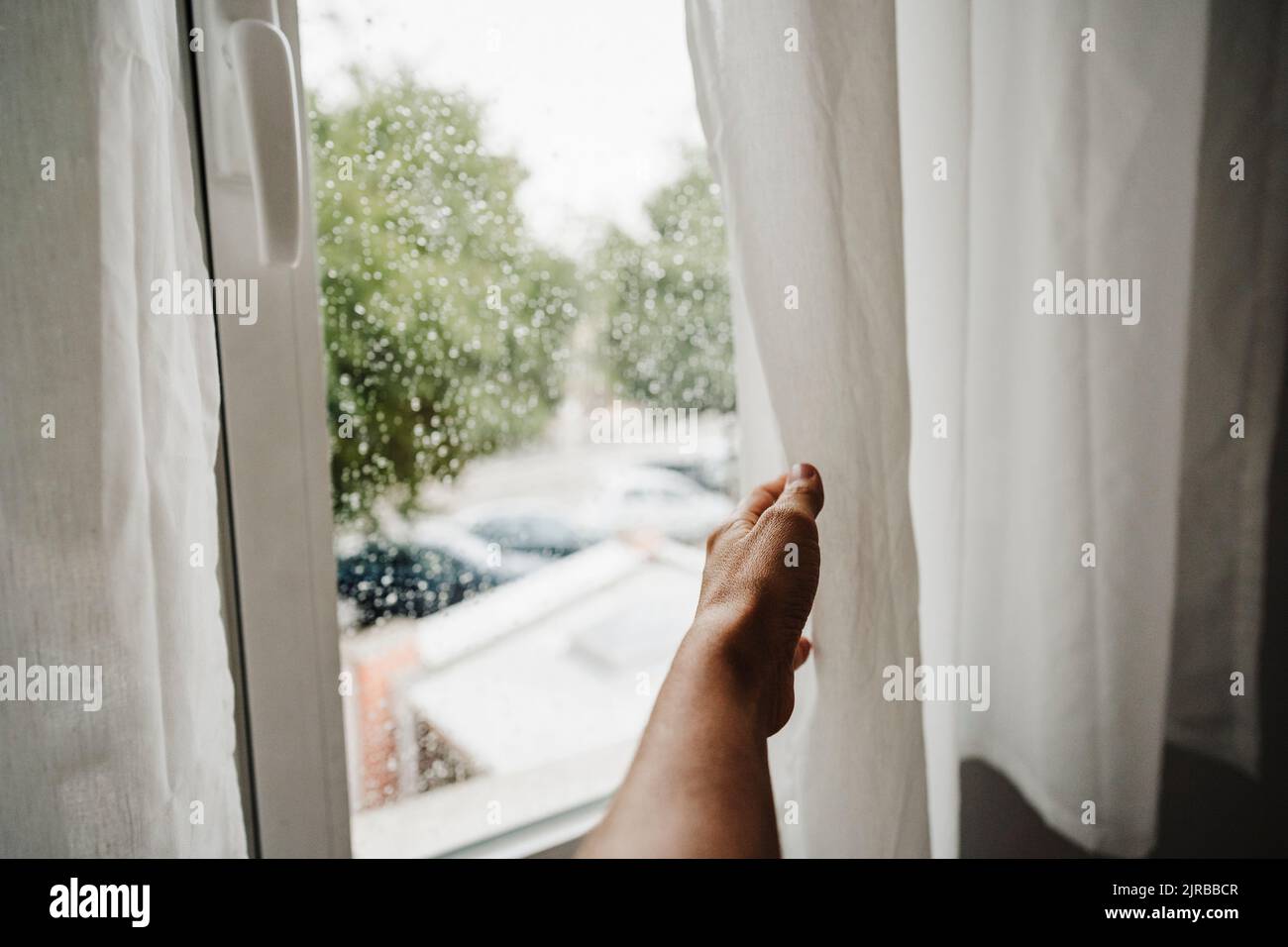 Hand of woman sliding curtain by window at home Stock Photo - Alamy