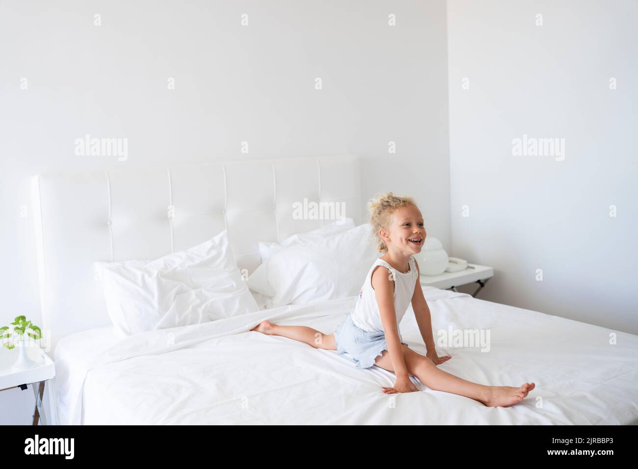 Happy girl doing splits on bed at home Stock Photo - Alamy
