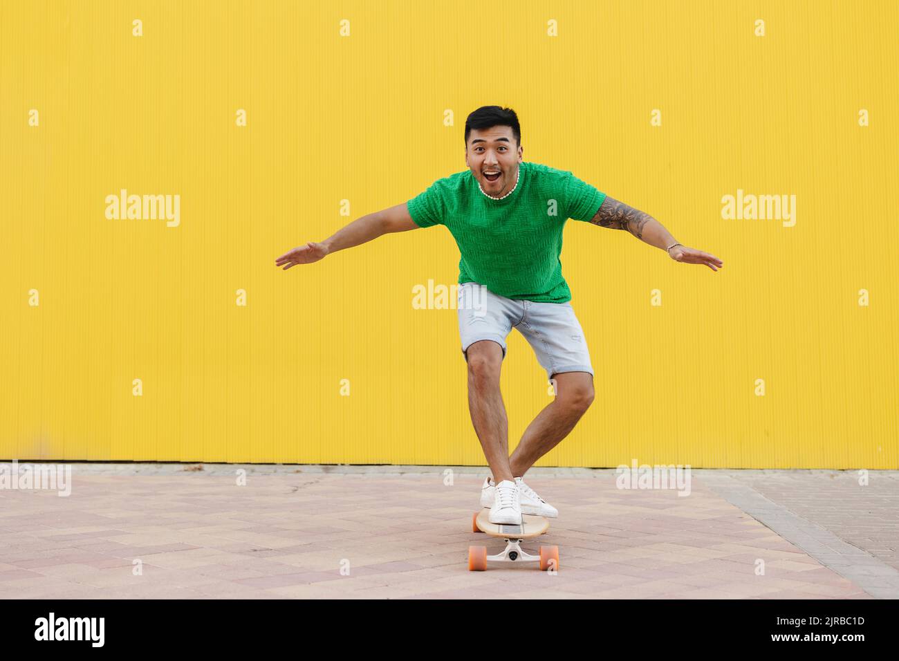 Happy young man balancing on skateboard Stock Photo - Alamy
