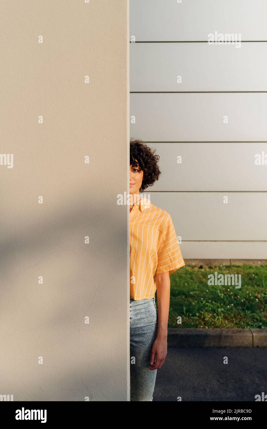 Woman standing behind wall on sunny day Stock Photo - Alamy