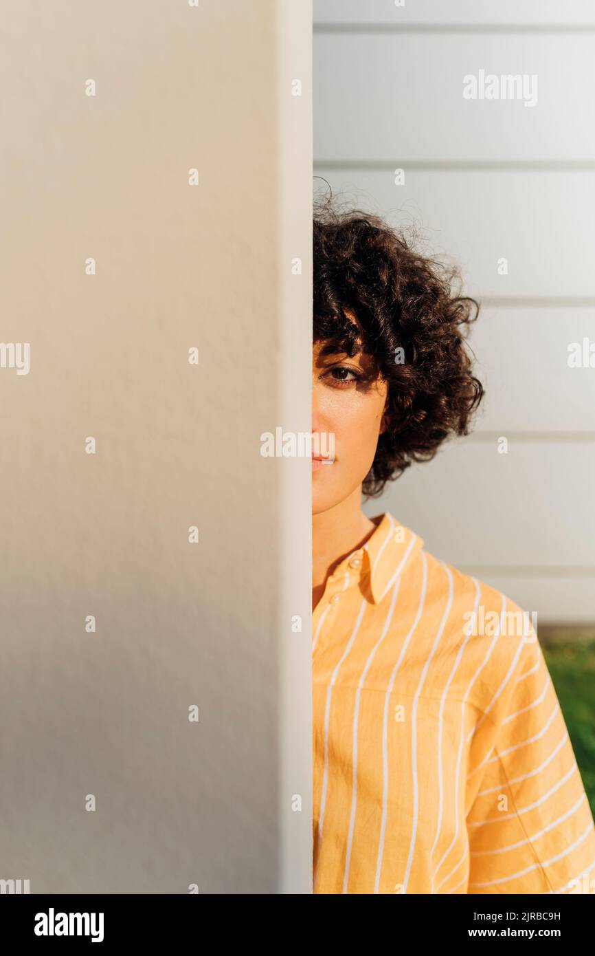 Young woman with curly hair behind wall Stock Photo - Alamy