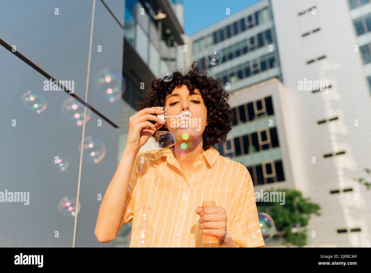 Young woman blowing bubbles through wand Stock Photo - Alamy
