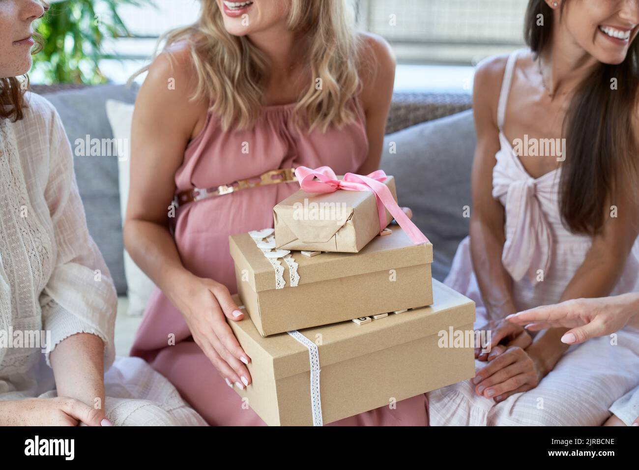 Pregnant woman holding gift boxes by friends at baby shower Stock Photo ...