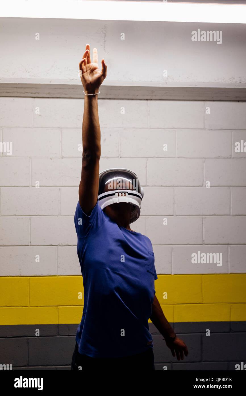 Young man with hand raised wearing astronaut helmet at subway Stock ...