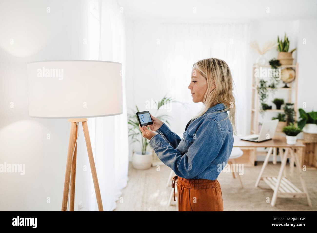 Woman checking electrical consumption of lamp at home Stock Photo - Alamy