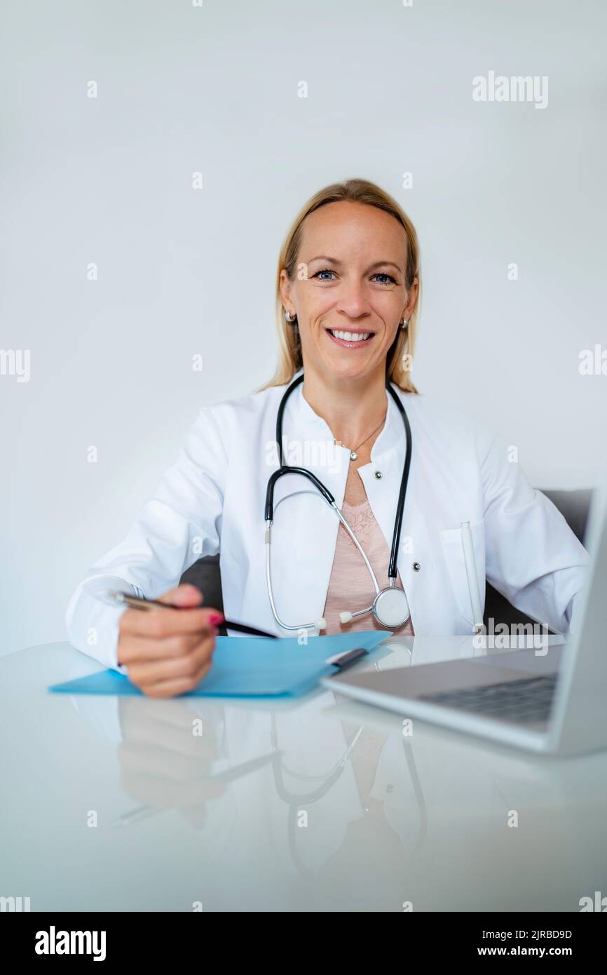 Portrait of smiling female doctor at desk in medical practice Stock ...