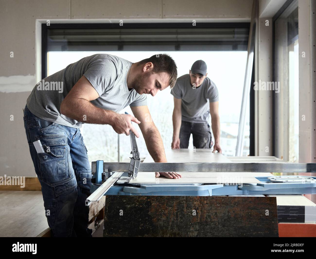 Tiler cutting tile with machine at construction site Stock Photo - Alamy