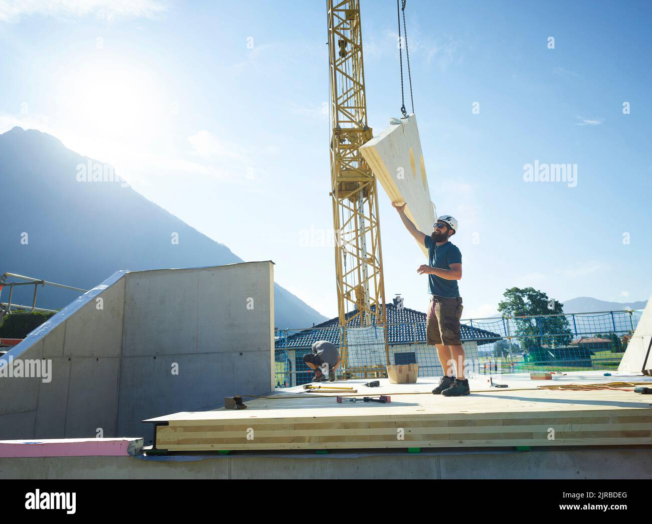 Carpenter working on rooftop with help of crane at construction site ...