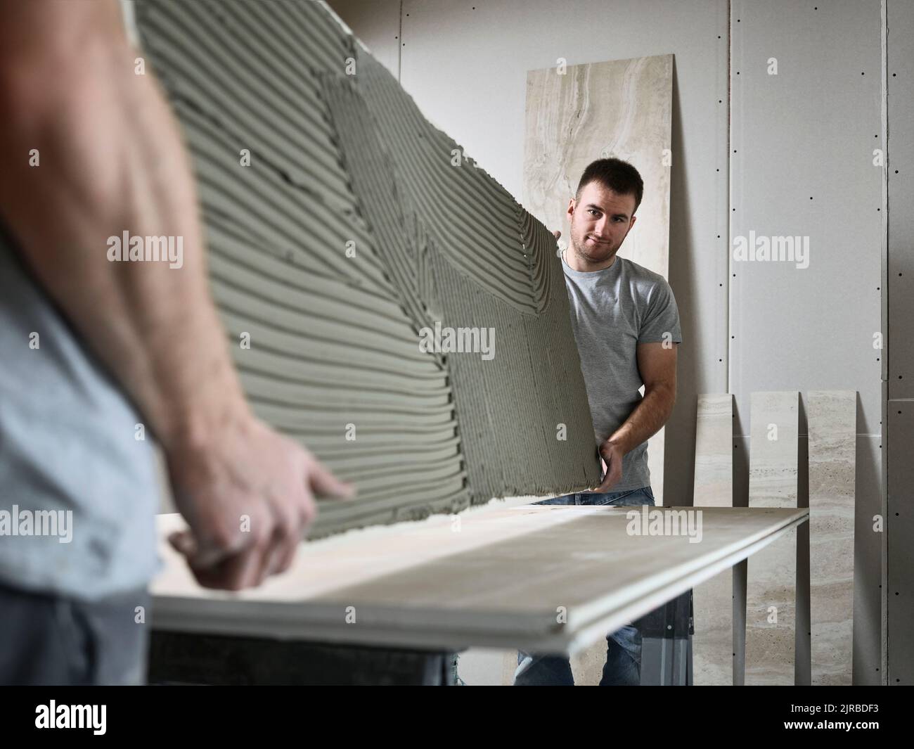 Tilers holding ceramic tile at table on construction site Stock Photo ...