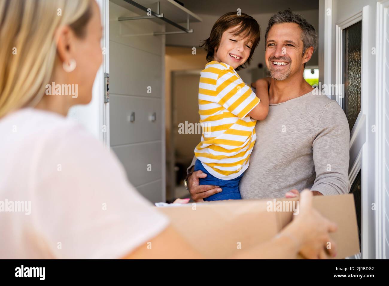 Happy man with son receiving parcel at the front door Stock Photo - Alamy