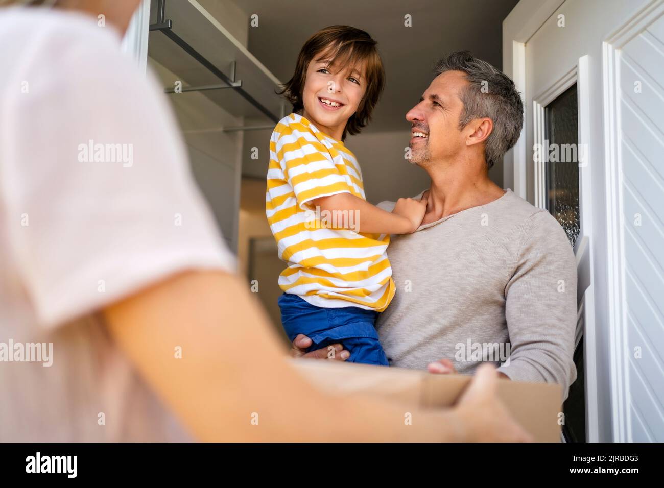 Man with son receiving parcel at the front door Stock Photo - Alamy