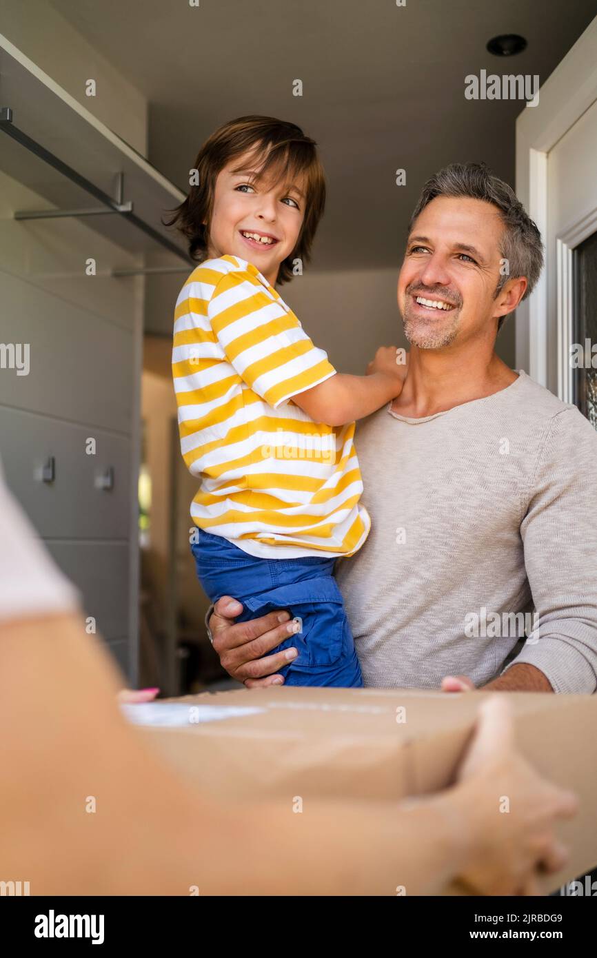 Man with son receiving parcel at the front door Stock Photo - Alamy