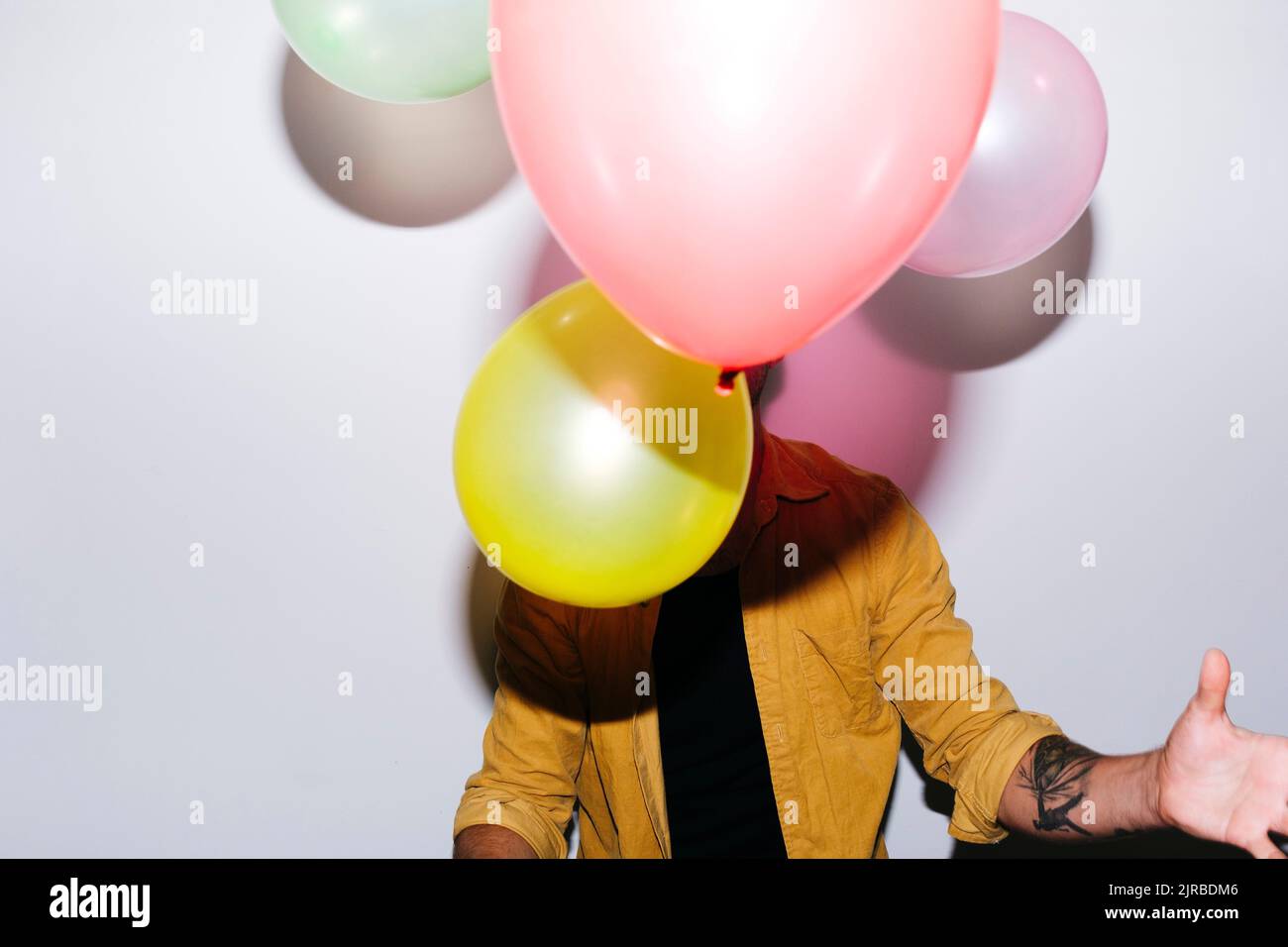 Man with balloons standing against white background Stock Photo - Alamy