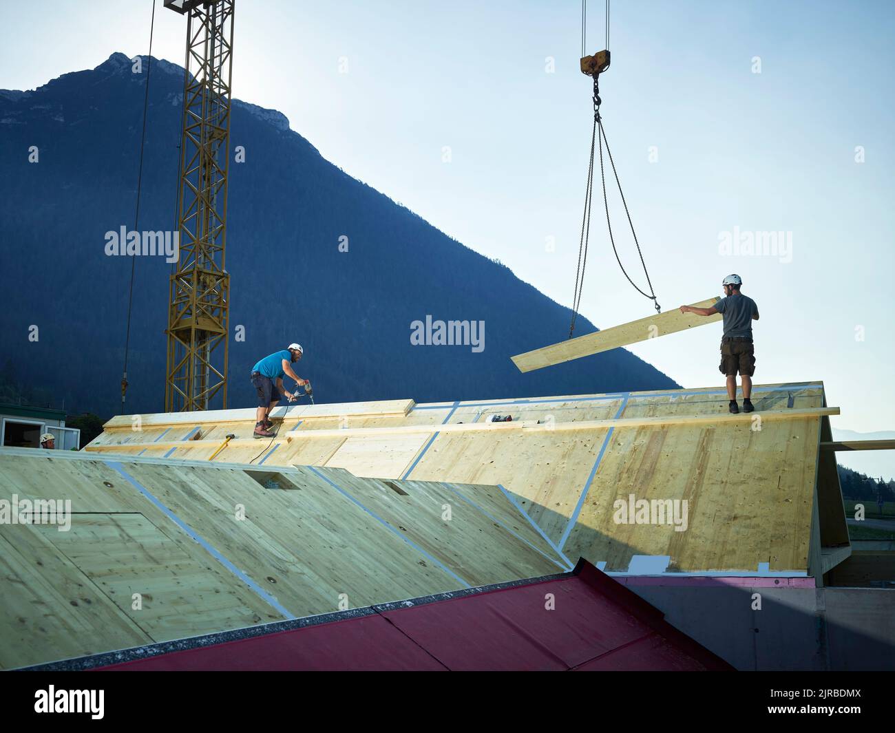 Workers installing roof with help of crane at construction site Stock ...