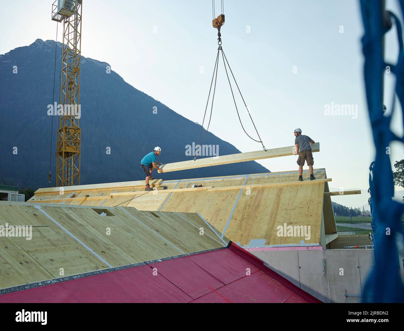 Carpenters installing rooftop with crane at construction site Stock ...