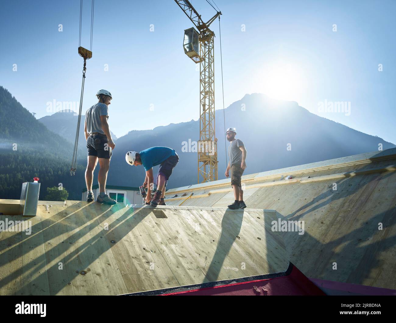 Carpenters working together on roof at construction site Stock Photo ...