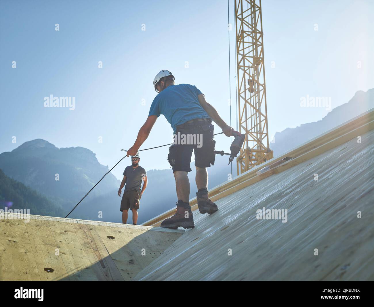 Carpenter holding drill working on roof at construction site Stock ...