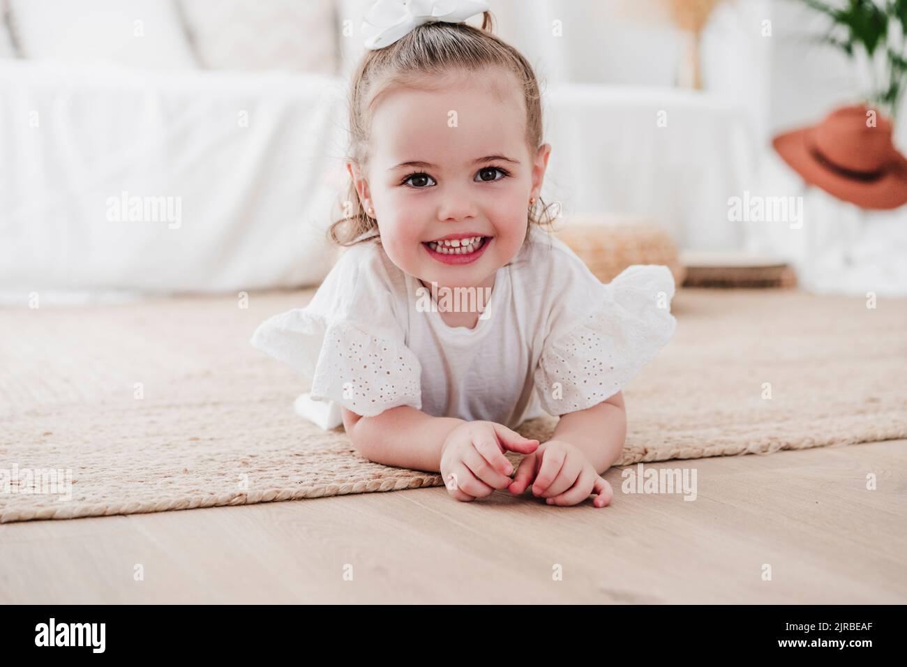 Cute little girl lying on carpet at home Stock Photo - Alamy