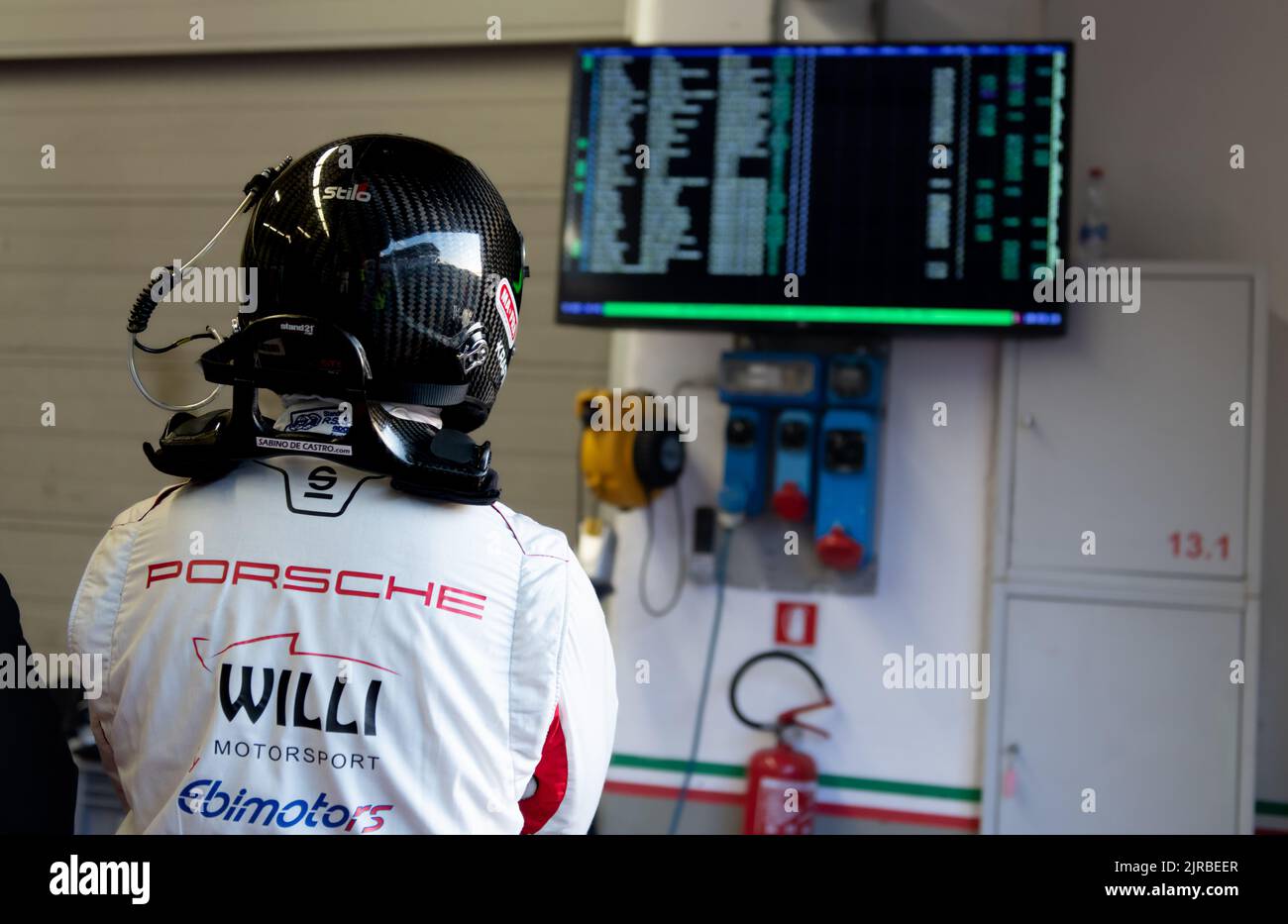 Race car driver in racing suit looking at display race info in team ...