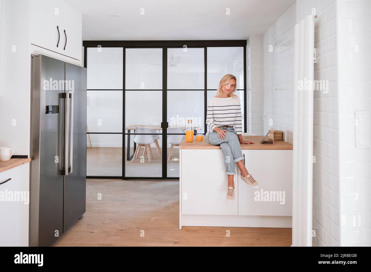Young woman sitting on counter in domestic kitchen at home Stock Photo ...