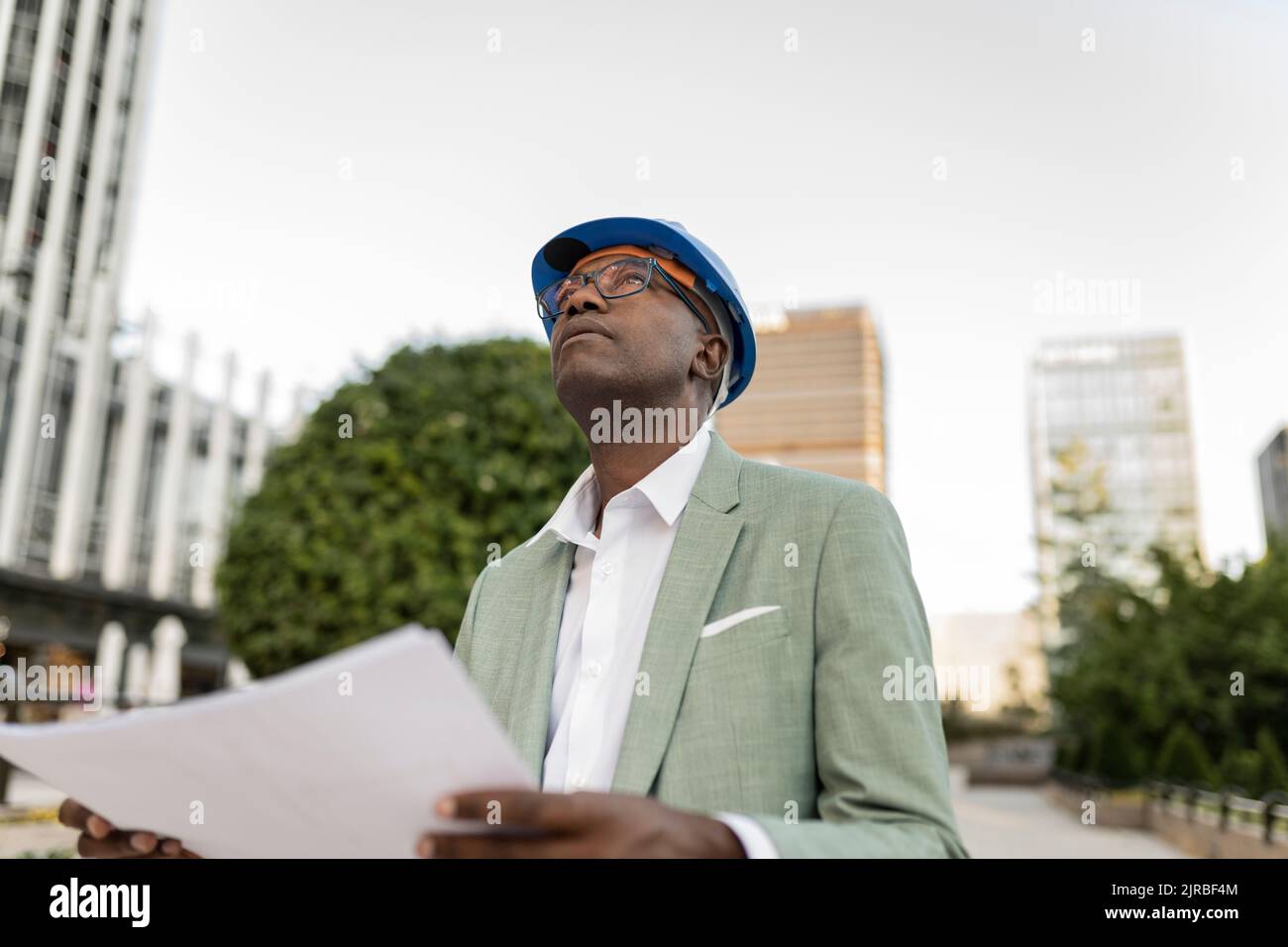 Engineer with blueprint at financial district Stock Photo - Alamy