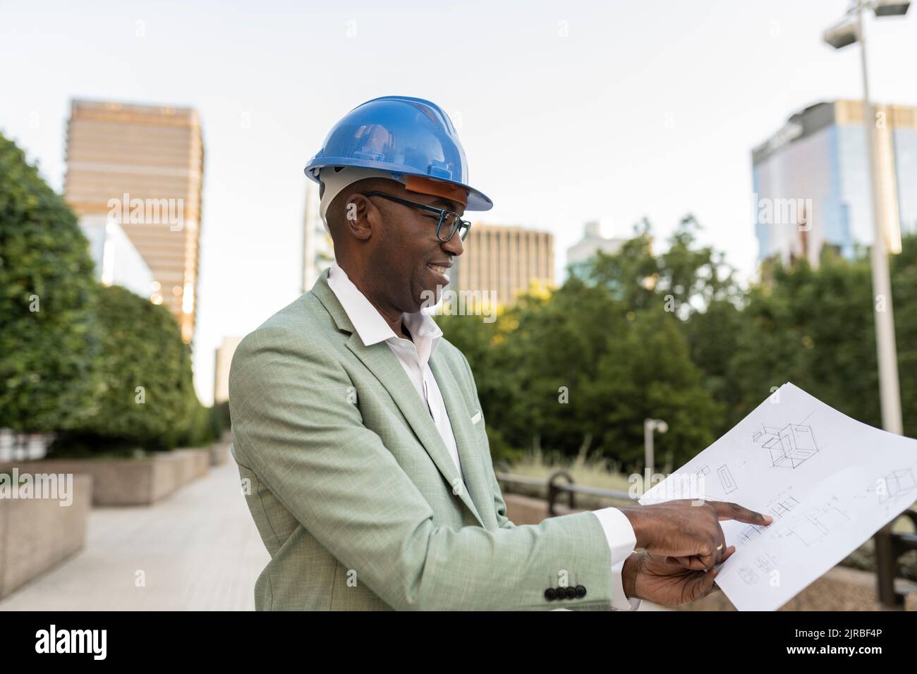 Smiling engineer explaining blueprint at financial district Stock Photo ...