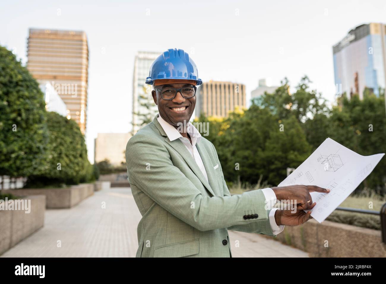 Happy engineer explaining blueprint at financial district Stock Photo ...