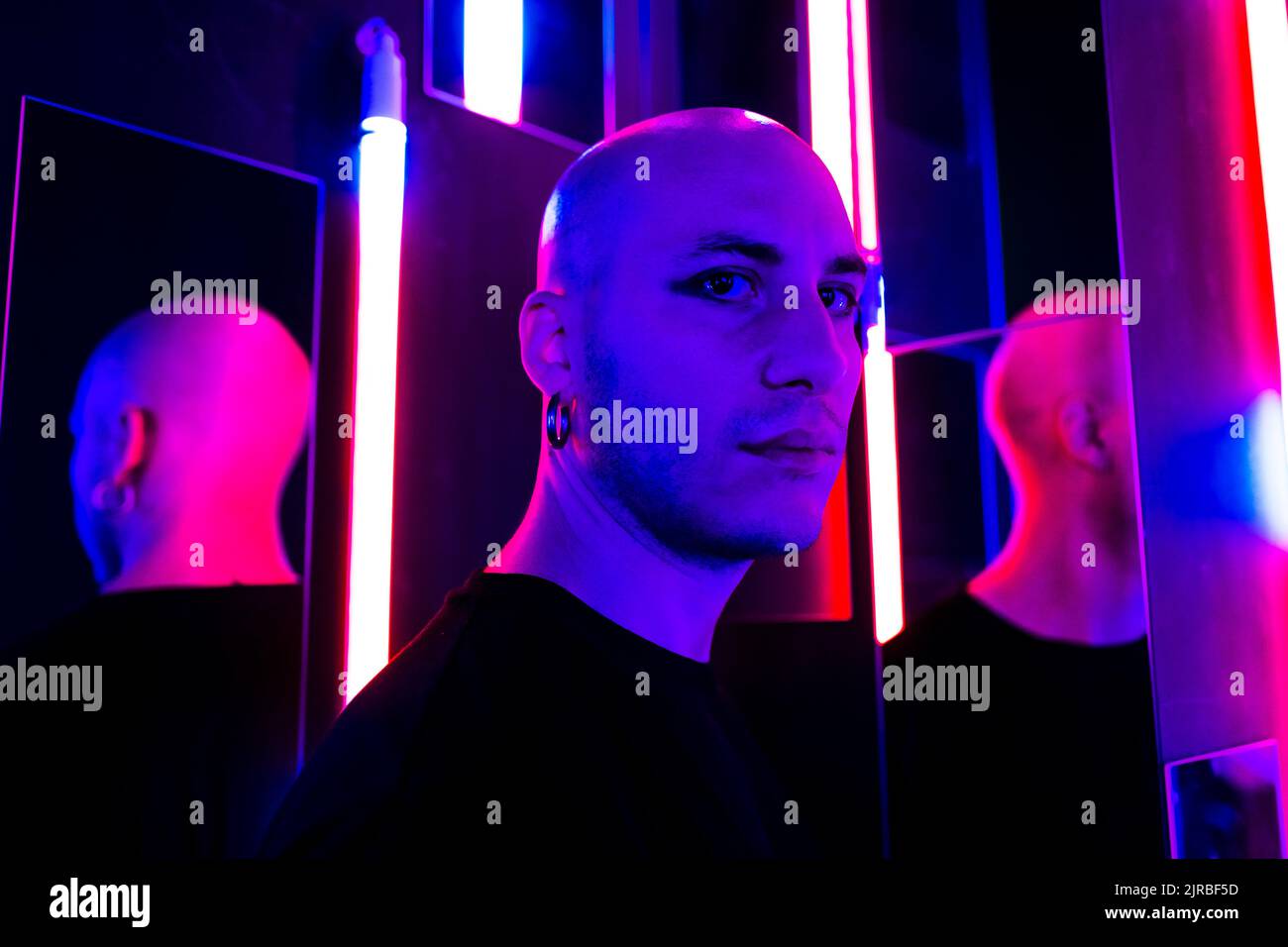 Serious shaved man near illuminated neon lights Stock Photo - Alamy