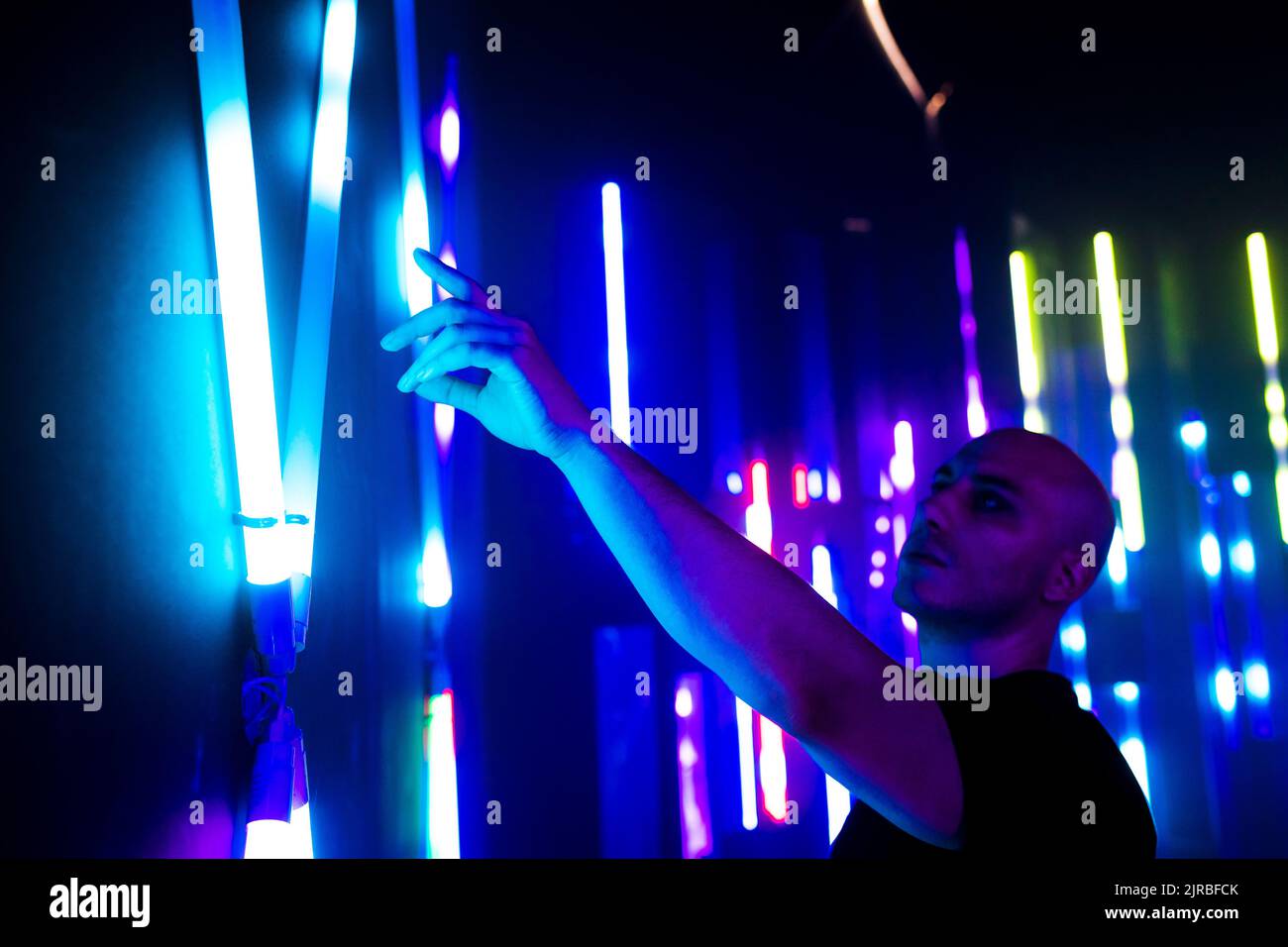 Man touching illuminated lights on wall Stock Photo - Alamy