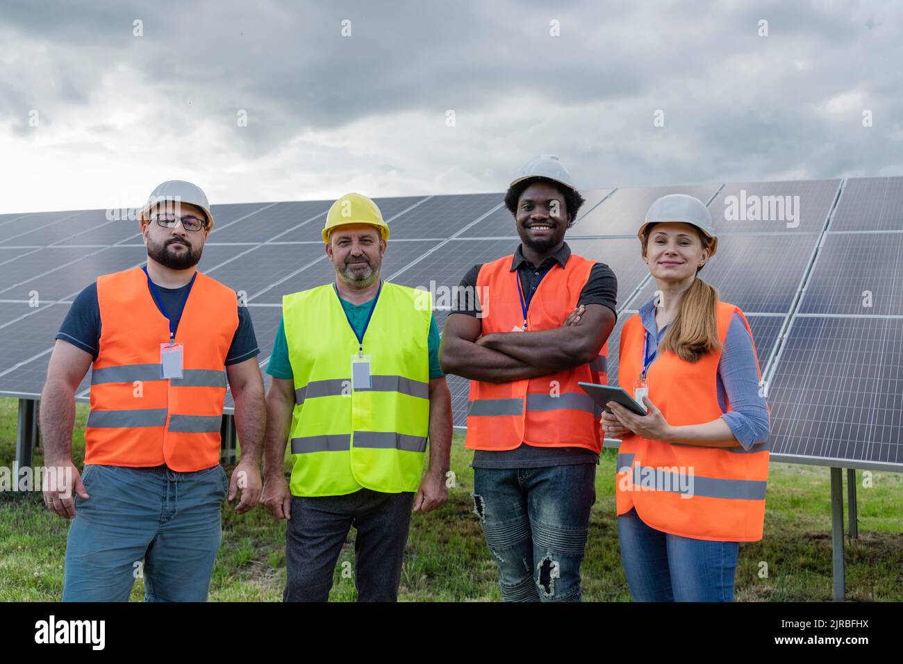 Smiling engineers standing together in front of solar panels Stock ...