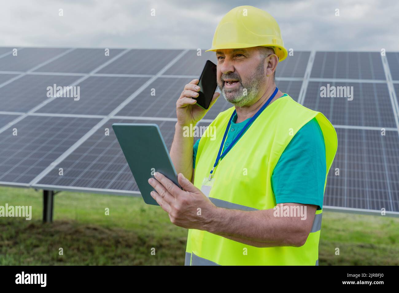 Engineer holding tablet PC talking on smart phone by solar panels Stock ...