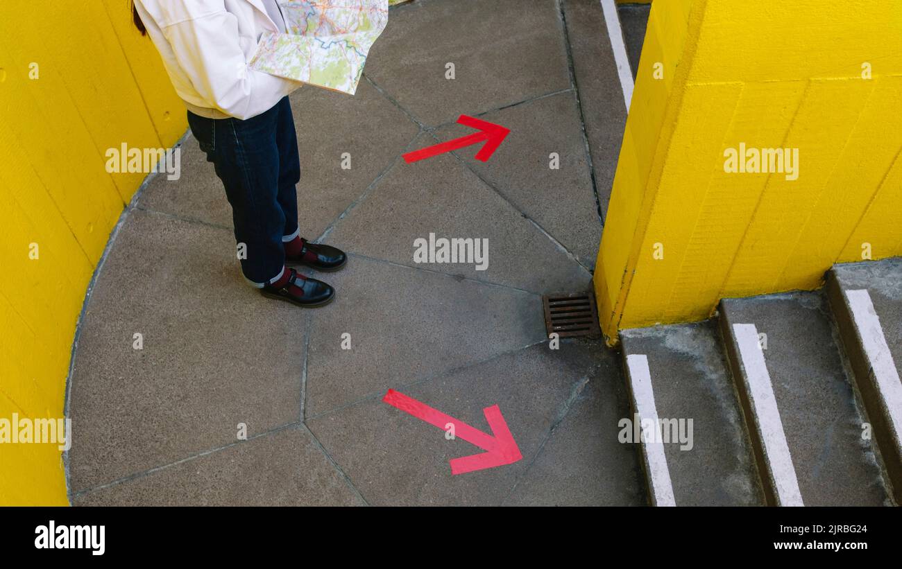 Woman holding map standing in front of arrow symbols Stock Photo - Alamy