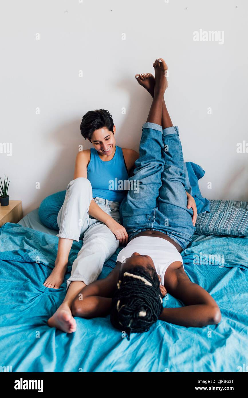 Happy woman talking with girlfriend on bed at home Stock Photo - Alamy