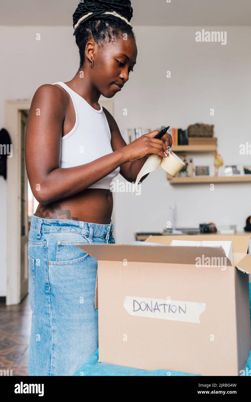 Woman with adhesive tape packing donation box on bed Stock Photo - Alamy