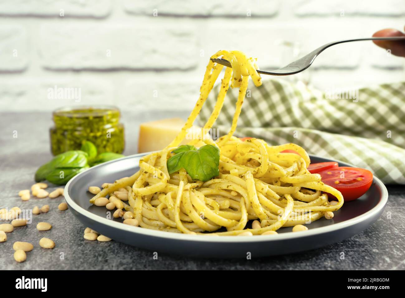 Pasta pesto with fork in dark plate on grey concrete background ...