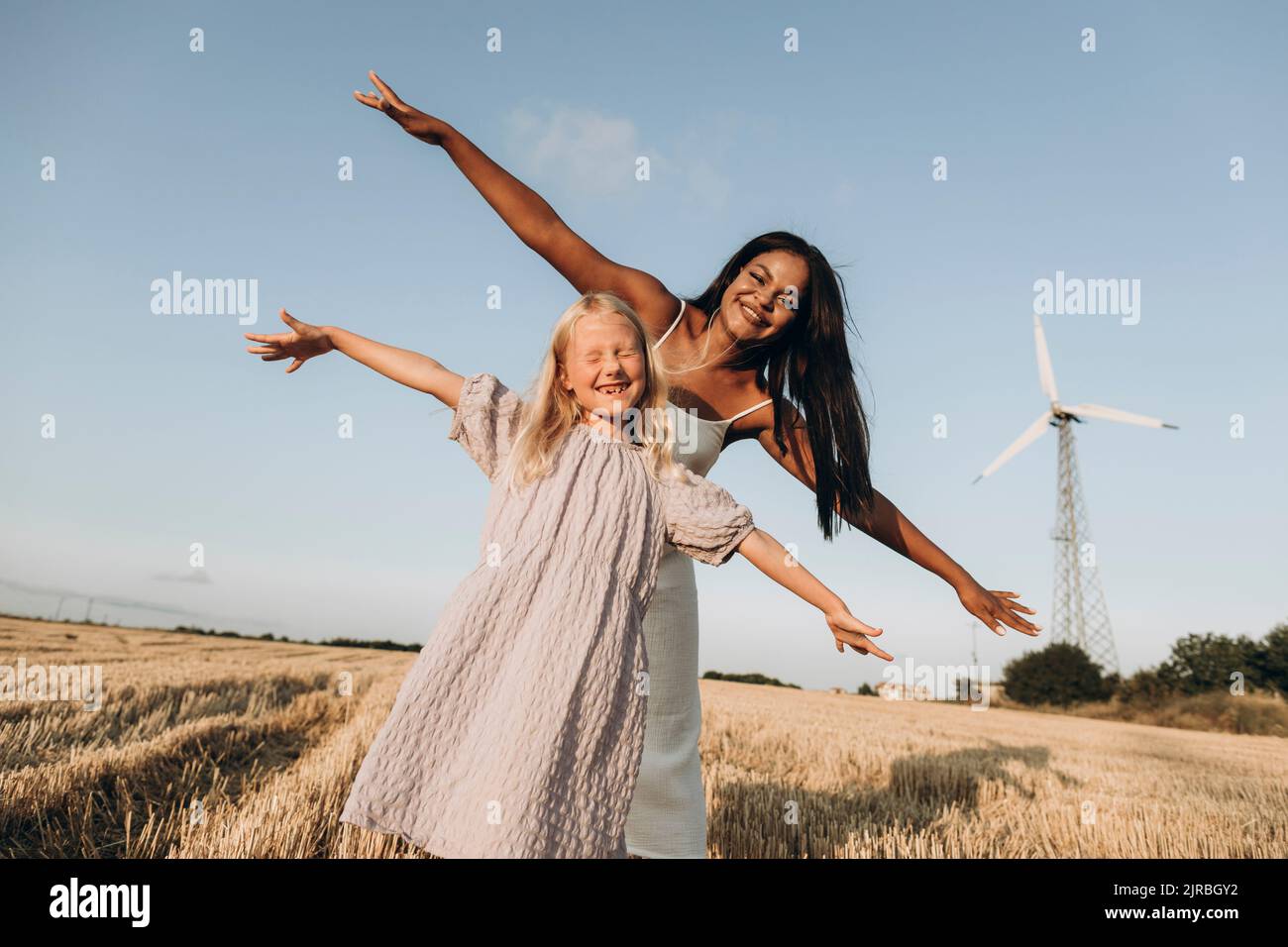 Cheerful woman and girl with arms outstretched at farm Stock Photo - Alamy