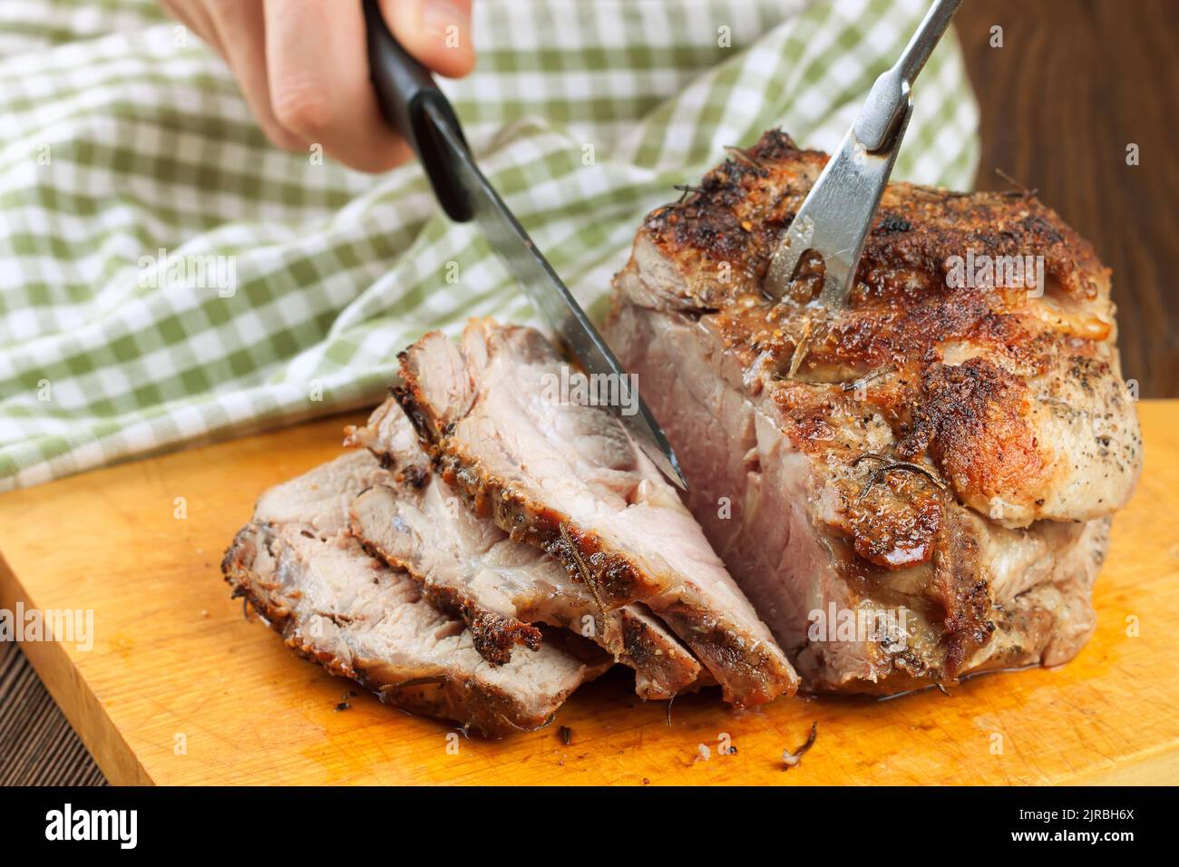 Baked pork meat with spices sliced on brown cutting board with knife ...