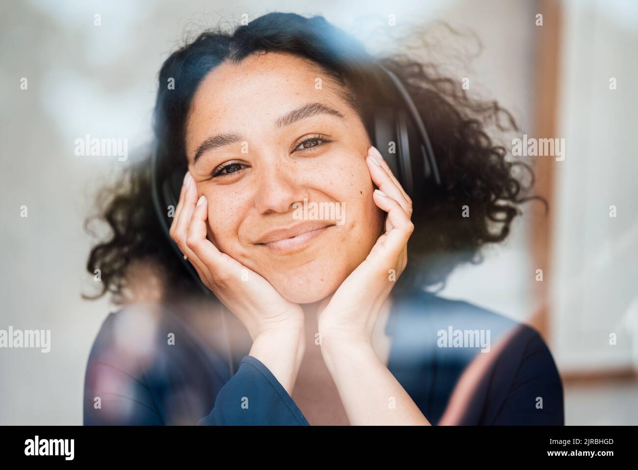 Happy curly hair woman listening music through headphones Stock Photo ...