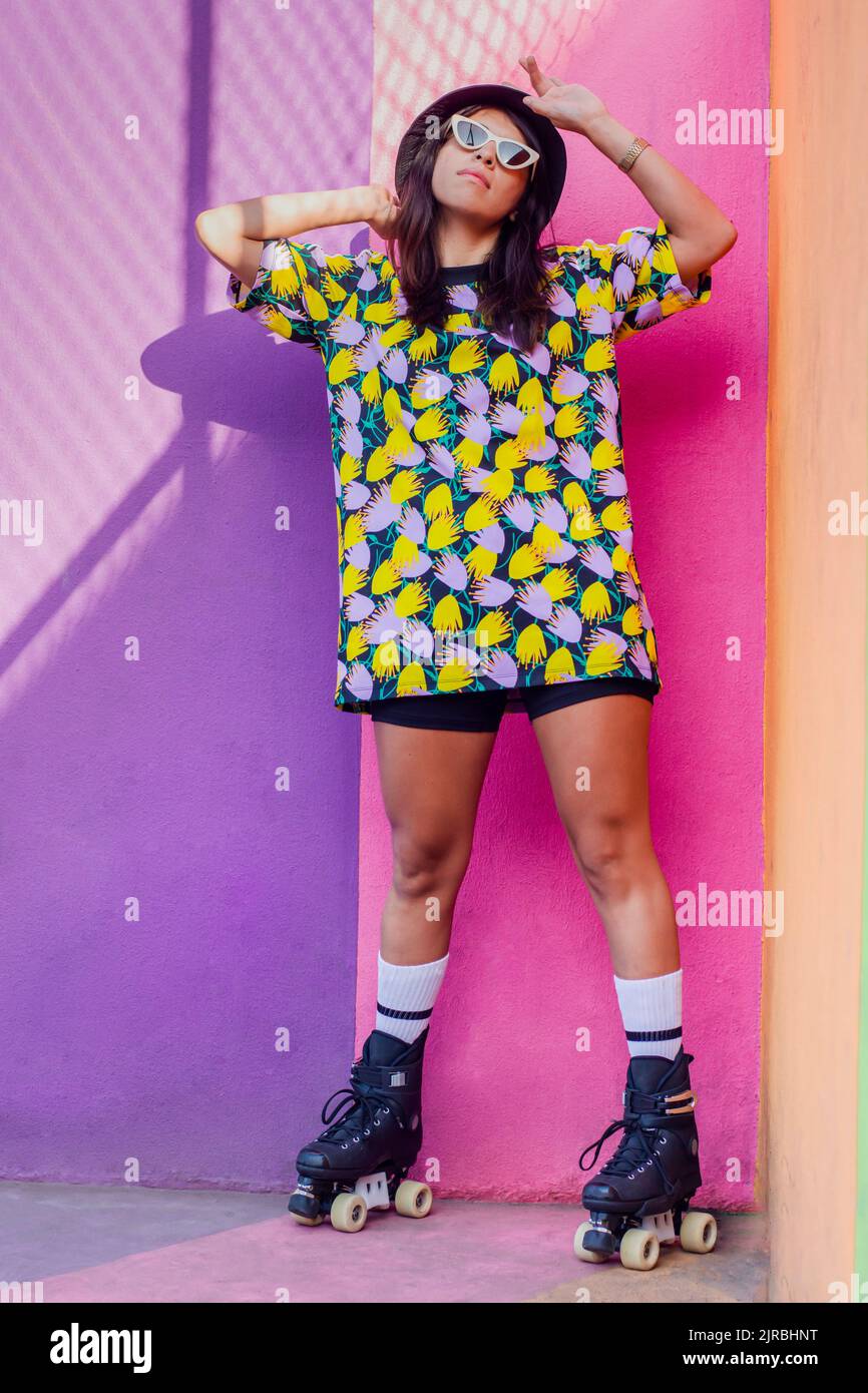 Woman wearing roller skates standing in front of multi colored wall ...