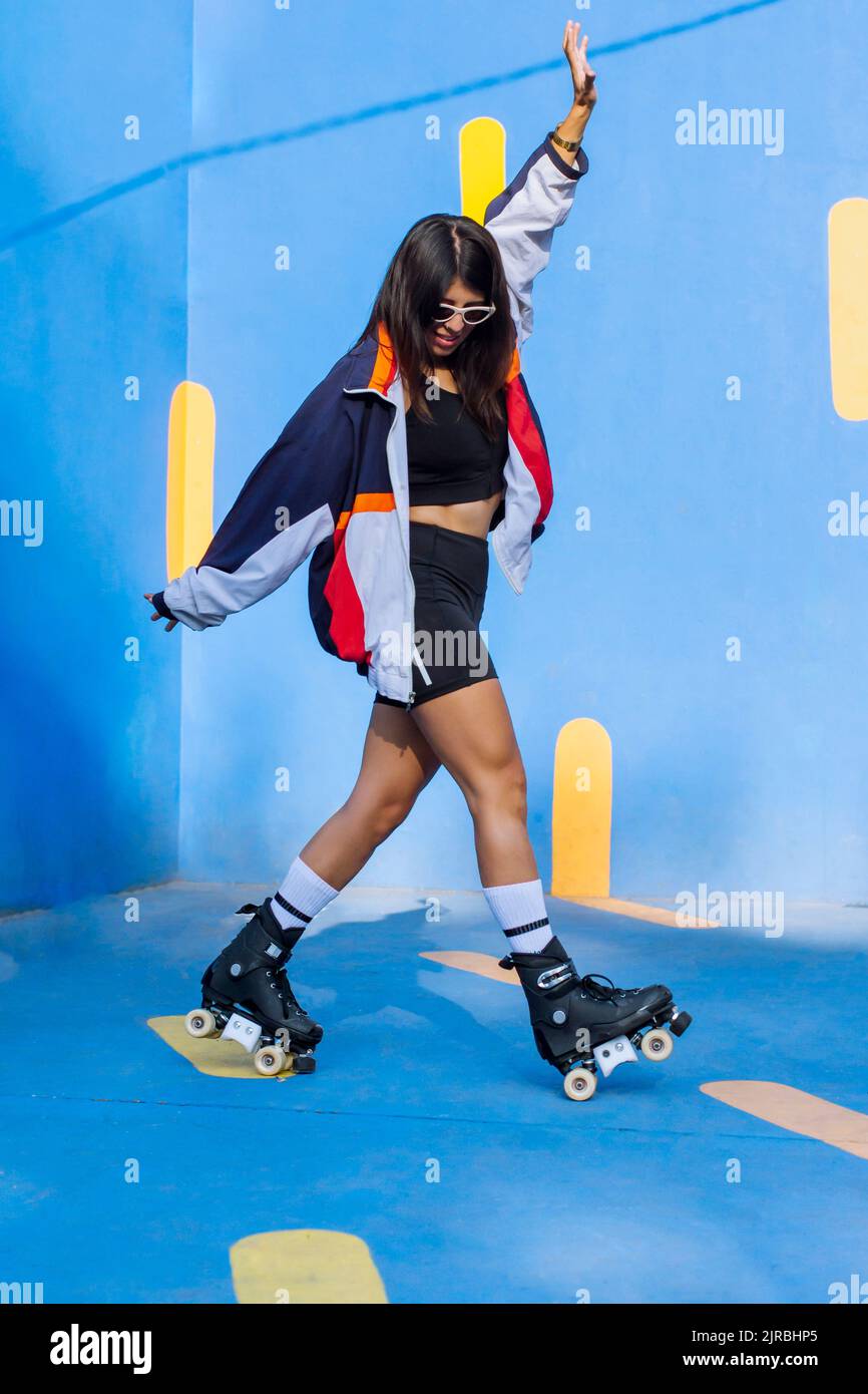 Woman wearing roller skates dancing by wall Stock Photo - Alamy