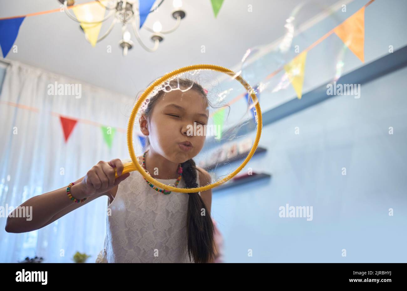 Birthday girl blowing bubbles from wand at home Stock Photo - Alamy