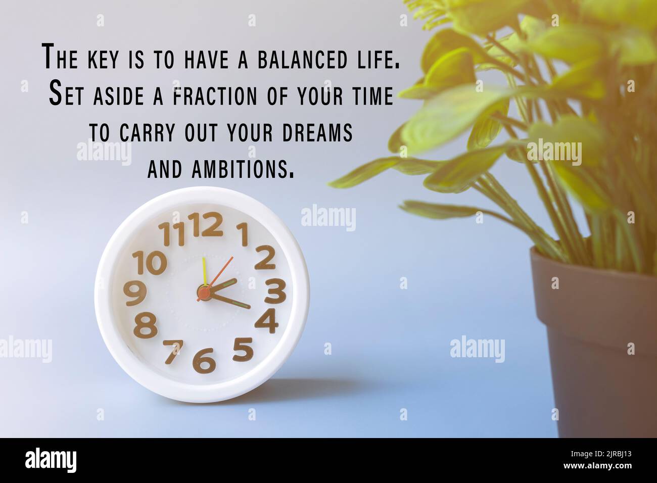 Motivational quote with white alarm clock and potted plant - The key is ...