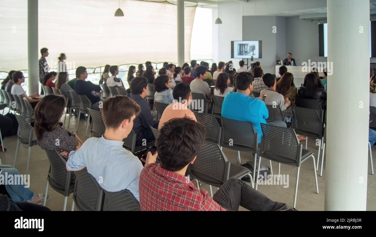 students paying attention to a lecture given by a woman, projecting ...