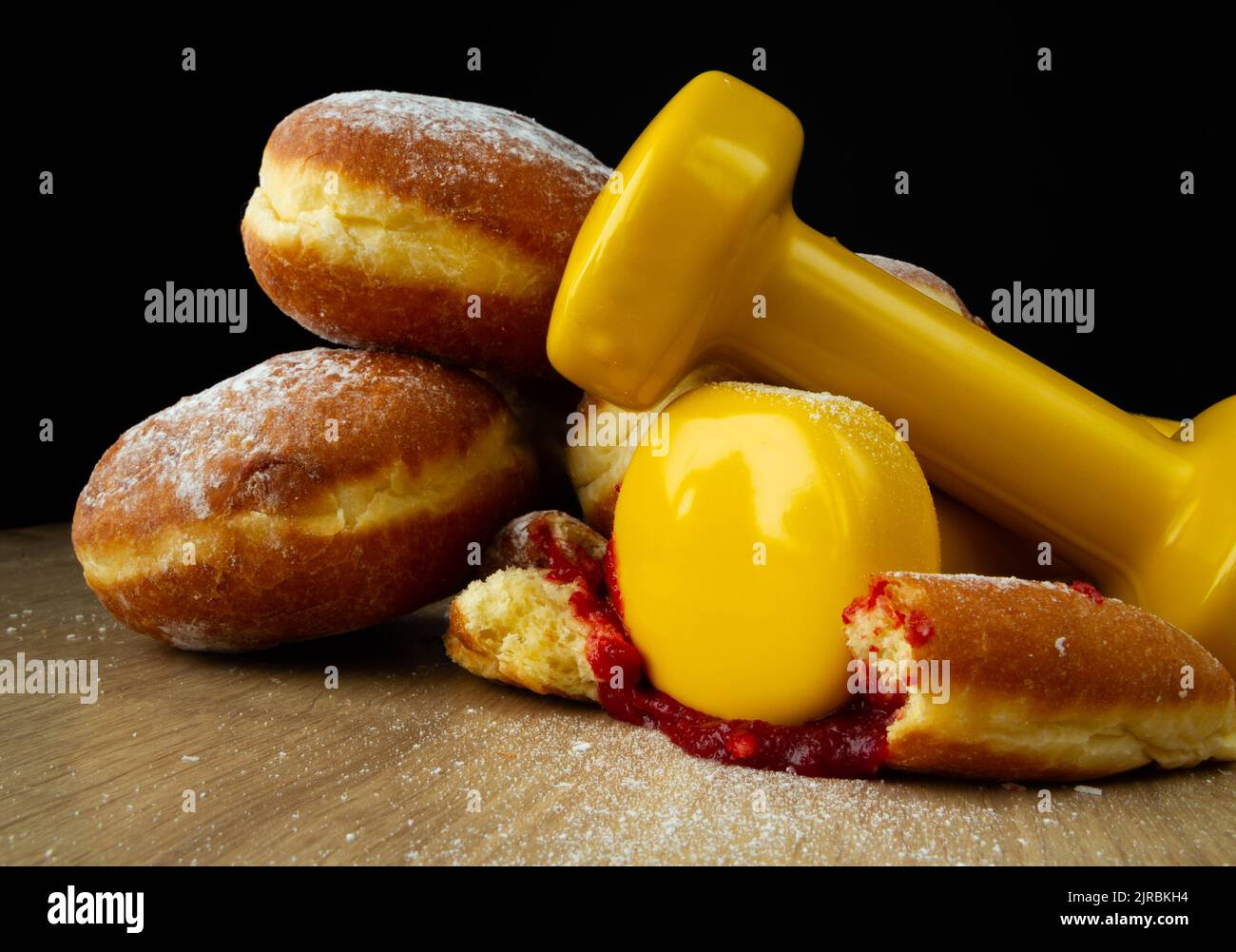 Gym dumbbells crushing Polish pączki deep-fried doughnuts. Fat Thursday ...