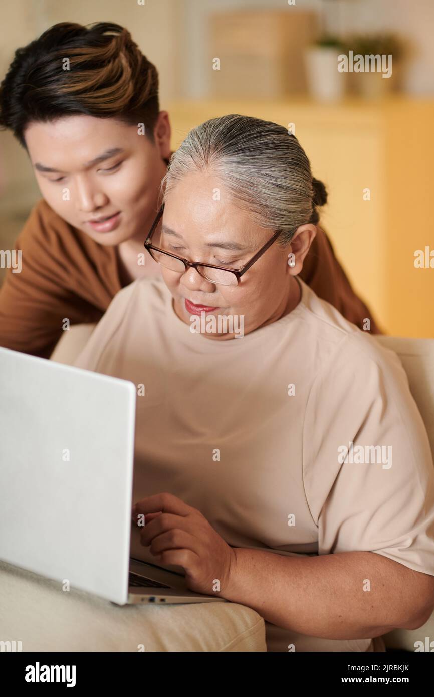 Young man teaching his grandmother how to work on laptop Stock Photo ...