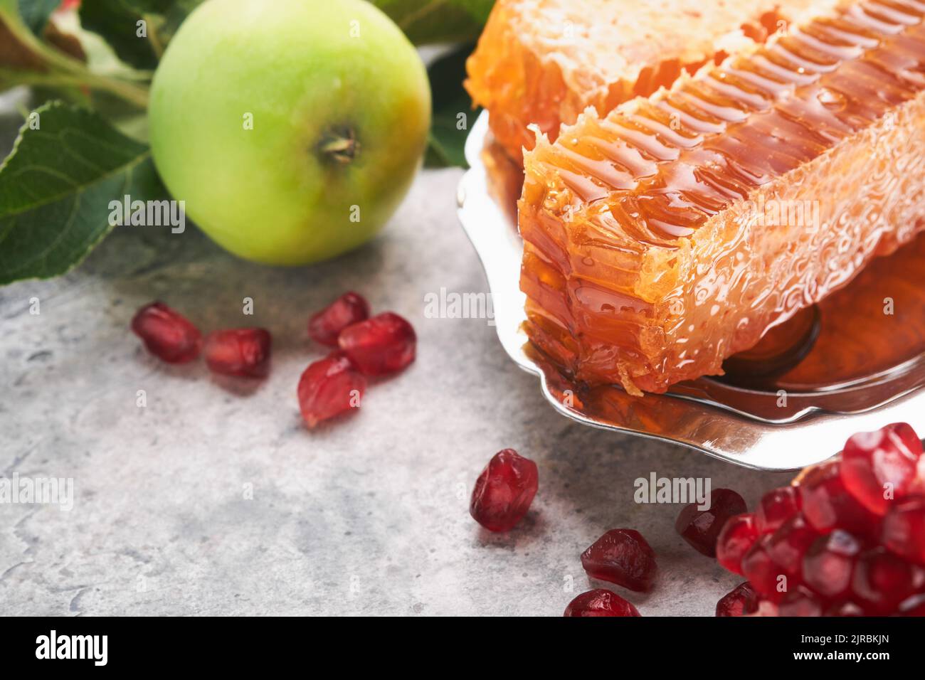 Rosh Hashanah. Honey jar, honeycomb, apple and pomegranate on gray old ...