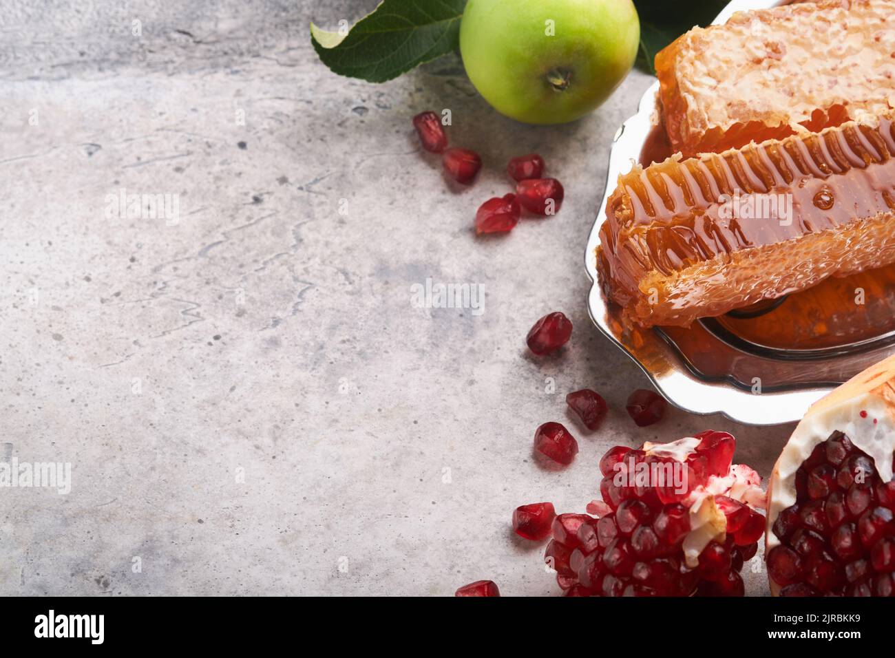 Rosh Hashanah. Honey jar, honeycomb, apple and pomegranate on gray old ...