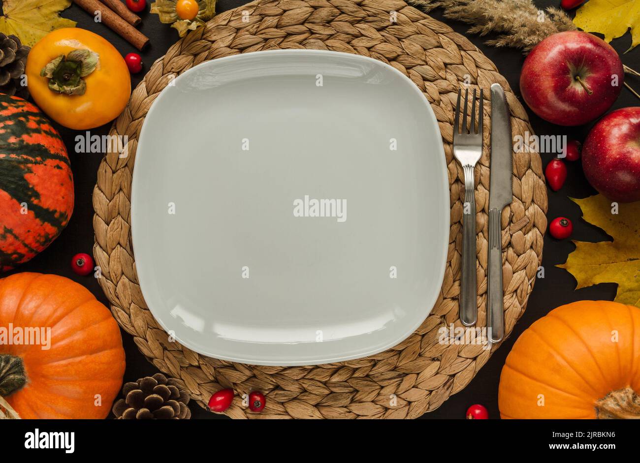 White plate and cutlery surrounded by pumpkins, leaves, apples ...
