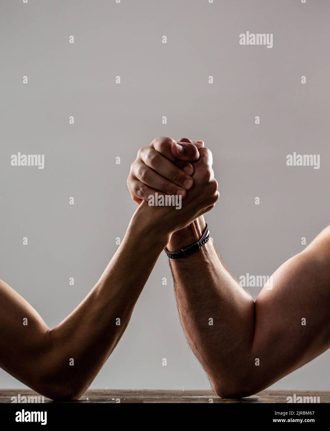 Two man's hands clasped arm wrestling, strong and weak, unequal match ...